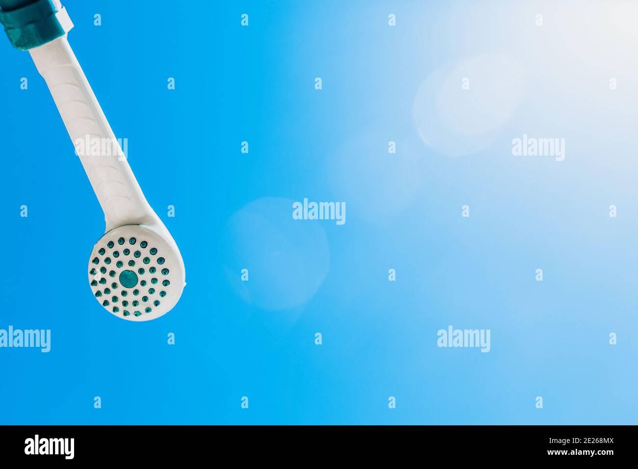 White shower head against a blue sunny sky - fresh shower after salt ...