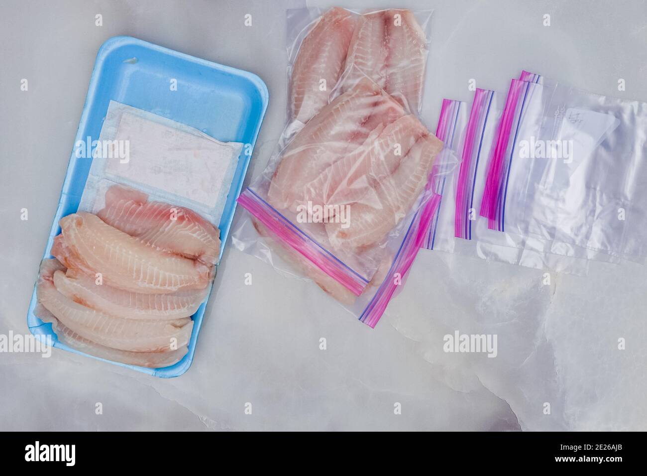 Fresh raw fish fillet in zip lock bags. Tilapia fillet on light marble ...