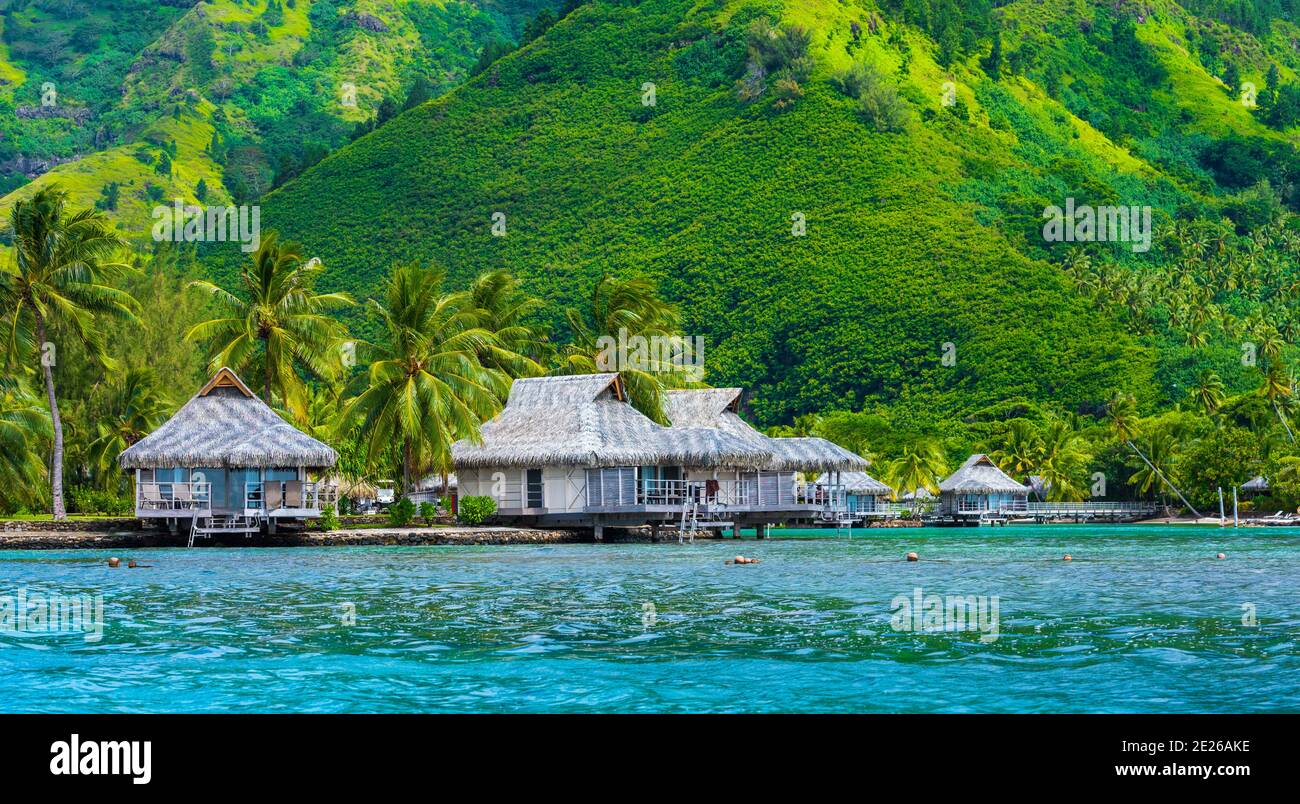 Thatched roof houses on a lagoon in the South Pacific at the foot of a ...