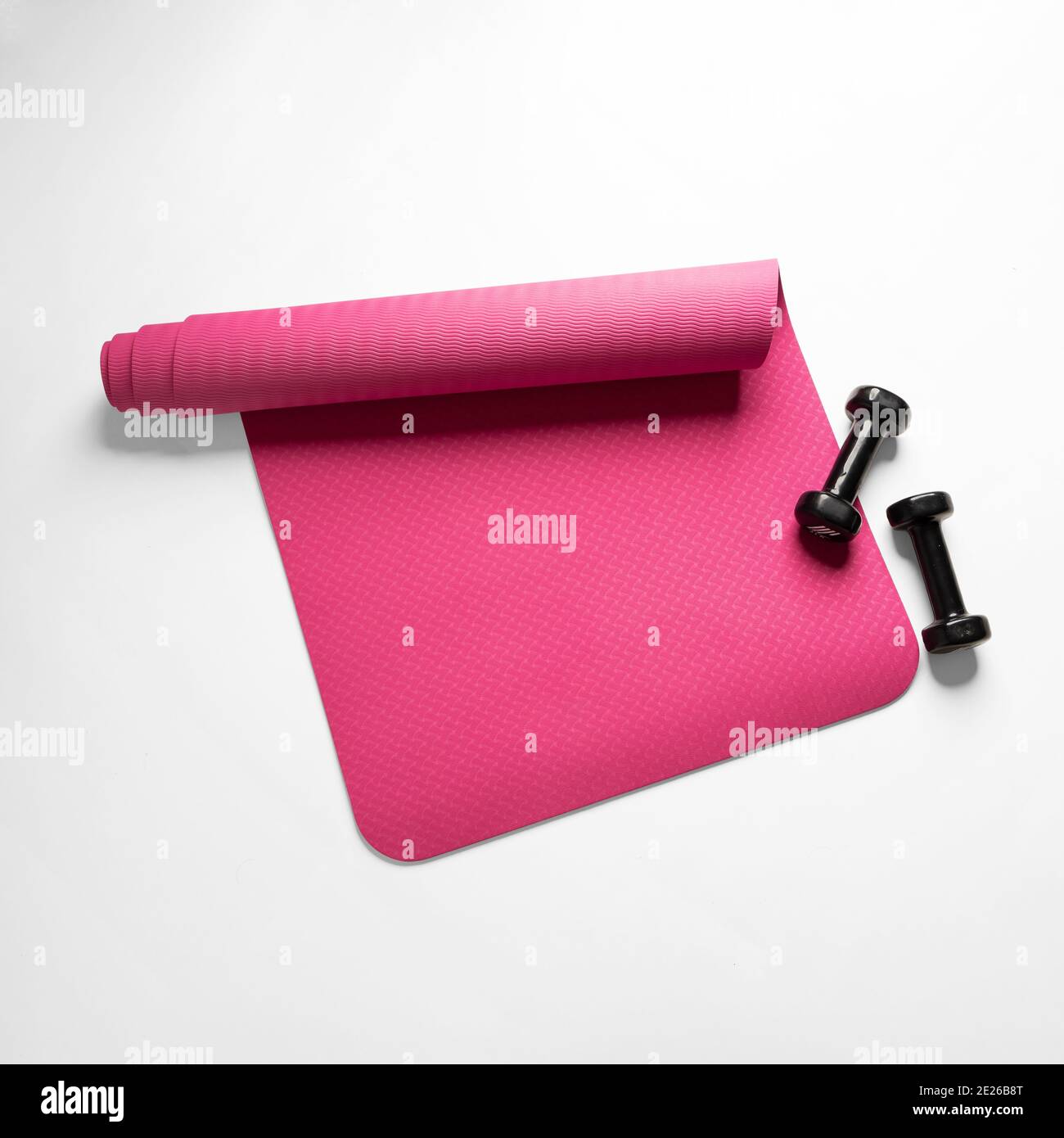 Top view of a pink fitness mat and two black dumbbells isolated on a ...