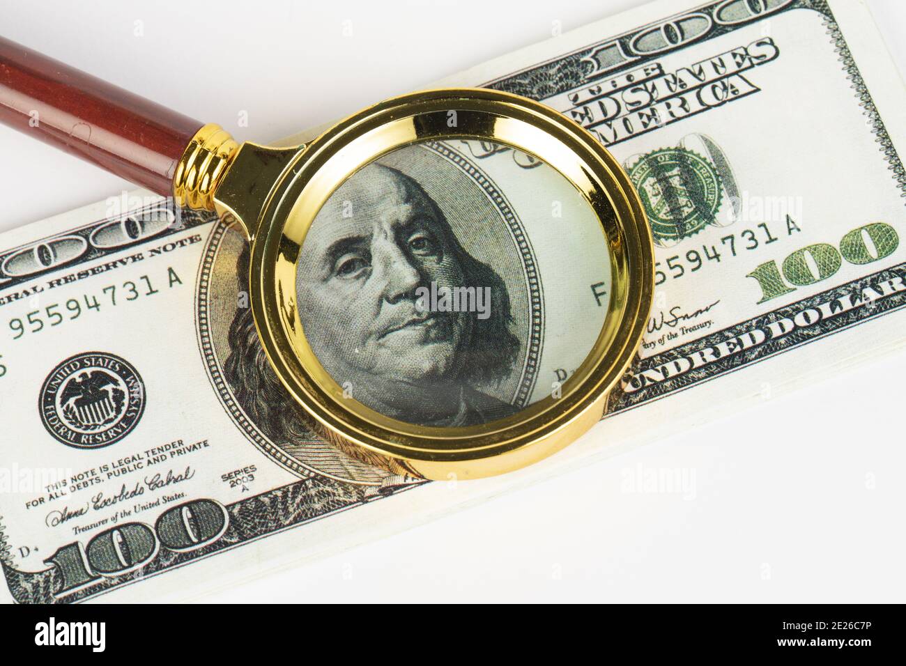 Top view of a magnifying glass over 100 dollar bill on white surface ...
