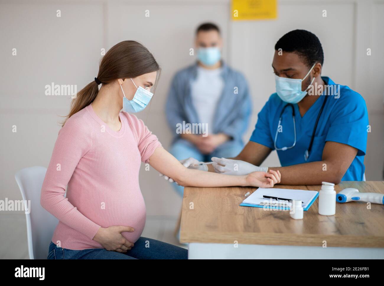 Black doctor giving Covid-19 vaccine injection to young pregnant woman ...
