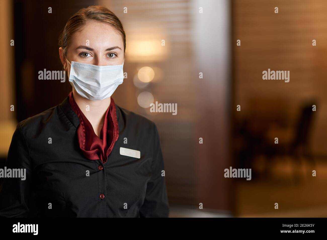 Copy-sapce photo of a serious waitress in uniform and with mask on ...