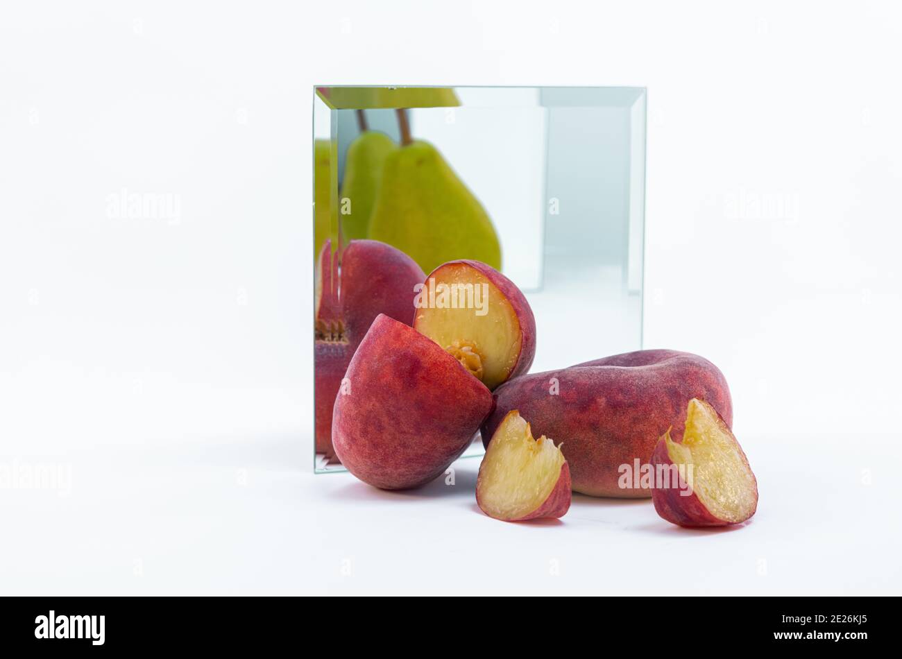 Closeup of pear and flat peaches near a mirror isolated on a white ...