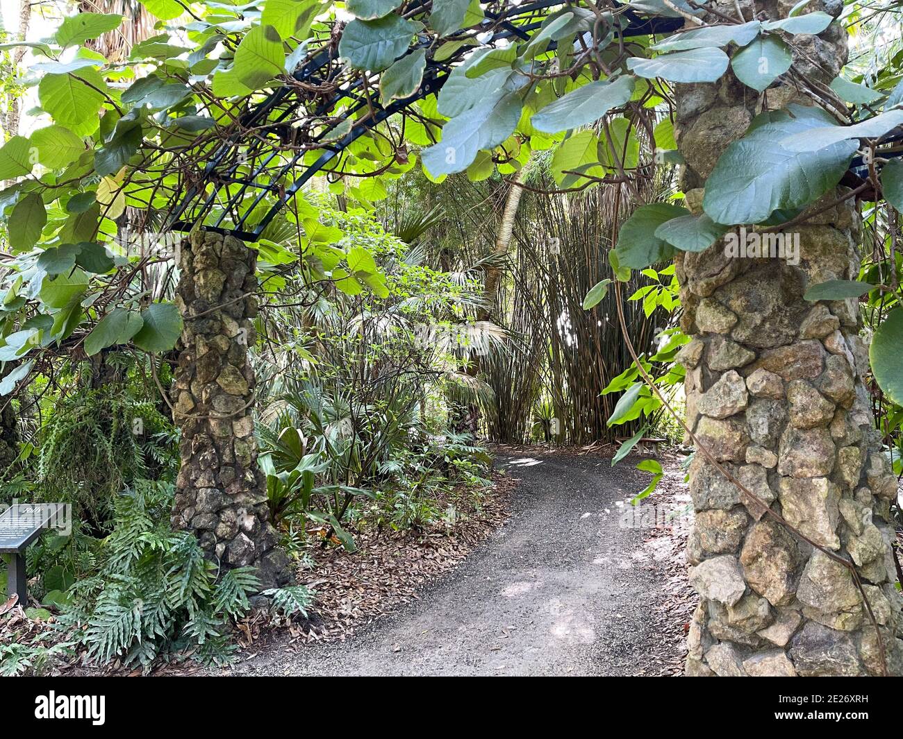 A rock pathway through a stone and metal trellis at a botanical garden ...