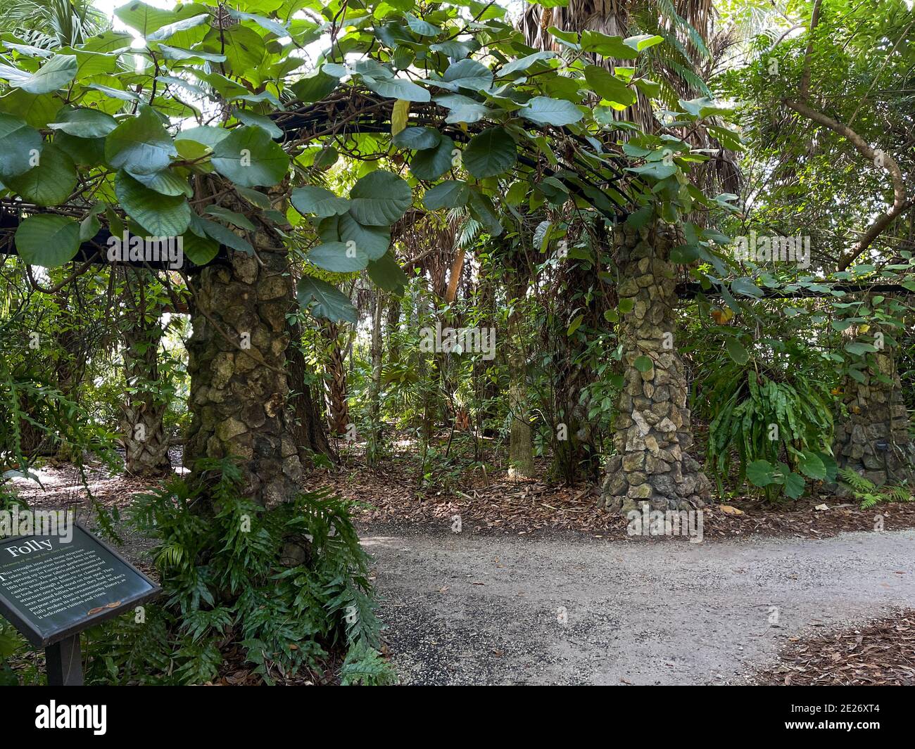 A rock pathway through a stone and metal trellis at a botanical garden ...