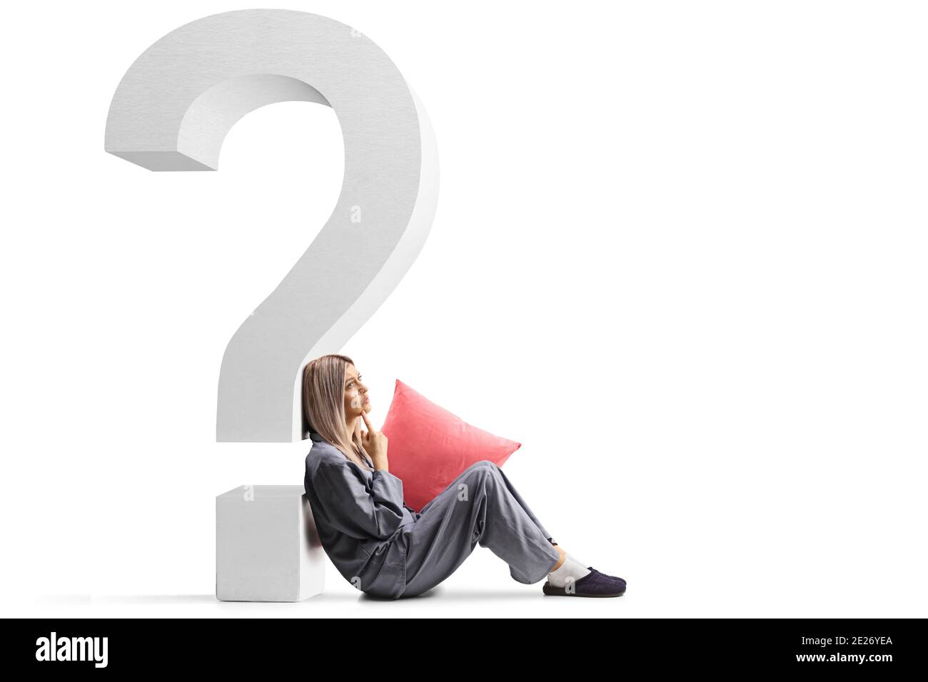 Young woman in pajamas sitting on floor and leaning on a question mark ...