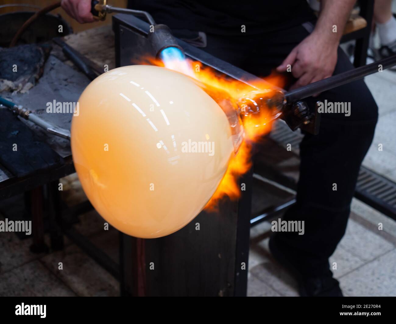 Glass artist forms the scorching glass with gas burner torch. Closeup ...