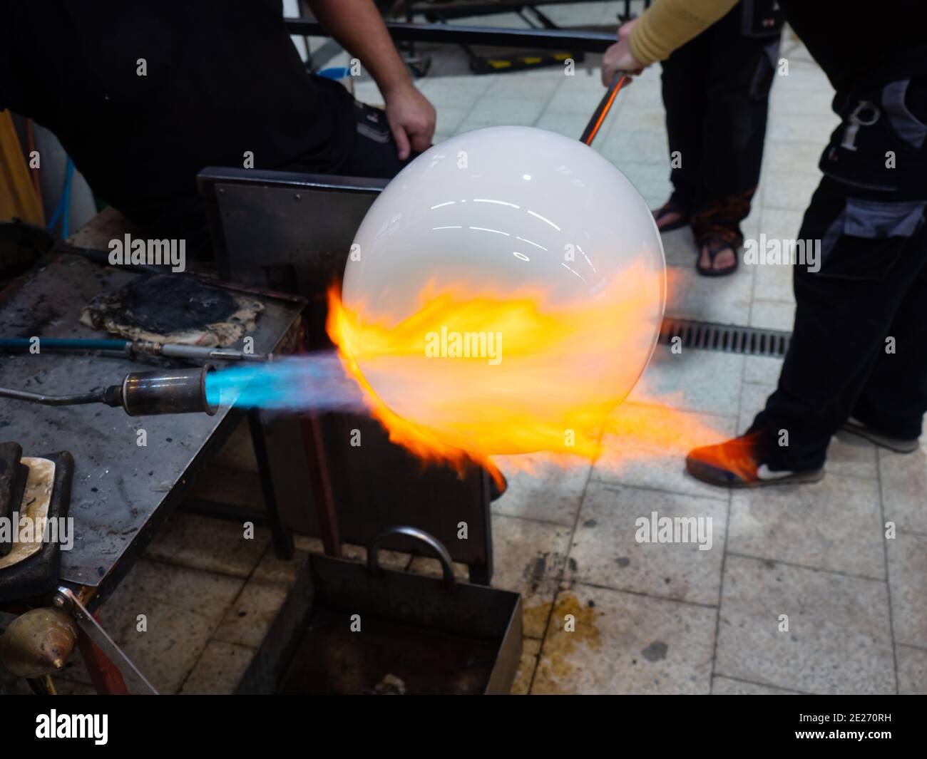 Glass artist forms the scorching glass with heats it with a gas burner ...