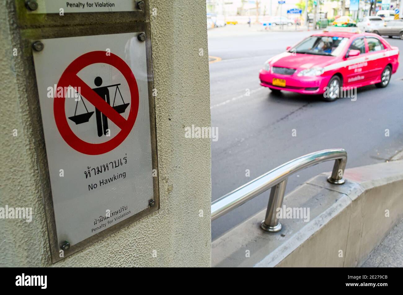 No hawking prohibited sign on the street of Bangkok. Pink taxi cab on a ...