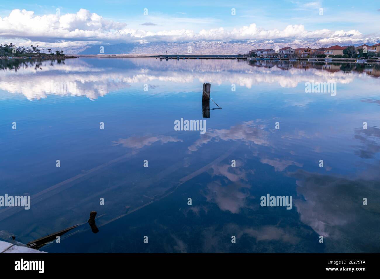 View of a sunken boat and coast in Nin lagoon. Reflection of clouds in ...
