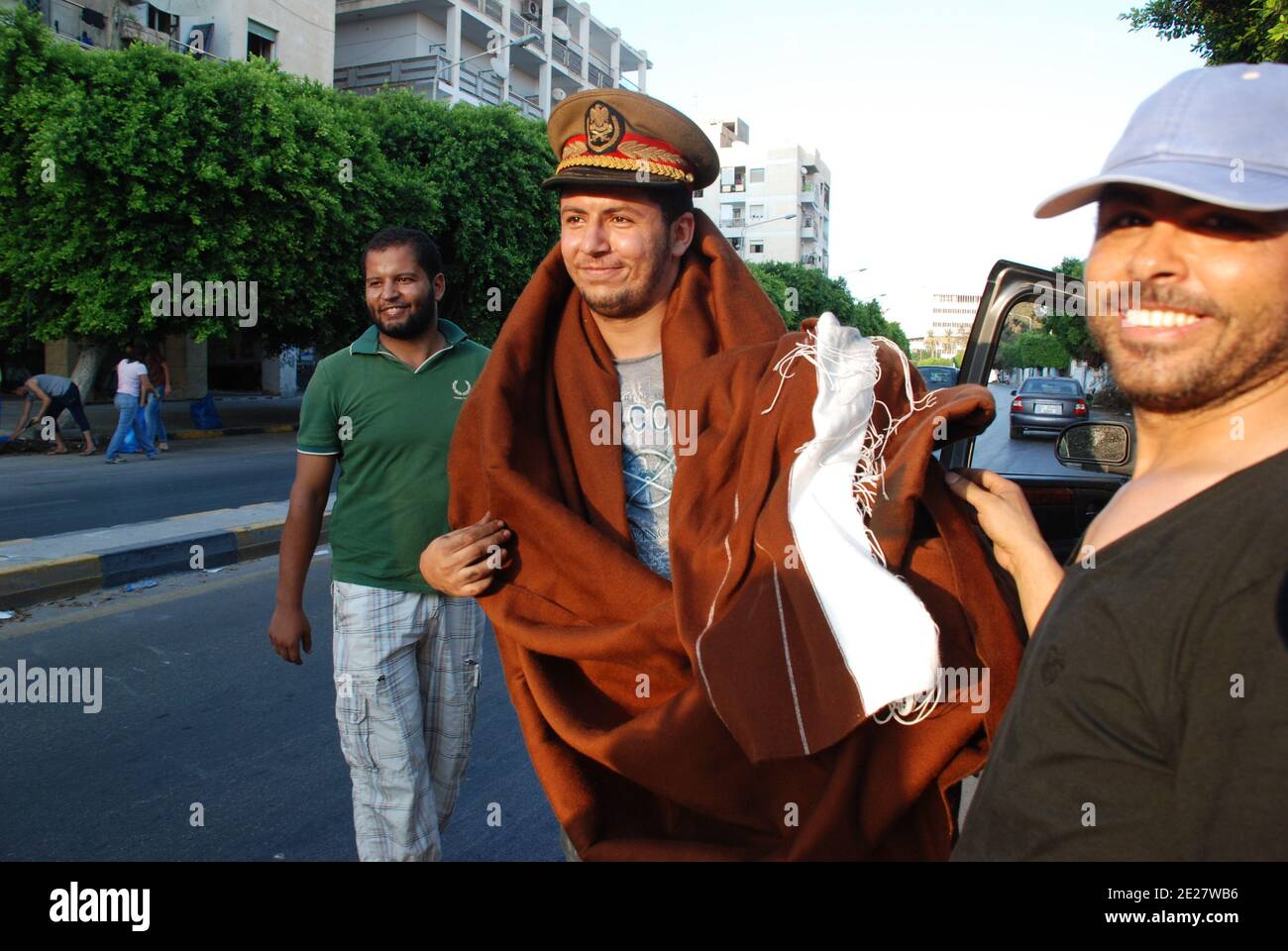 A Libyan man shows leader Gaddafi's military cap and tribal alfit worn ...