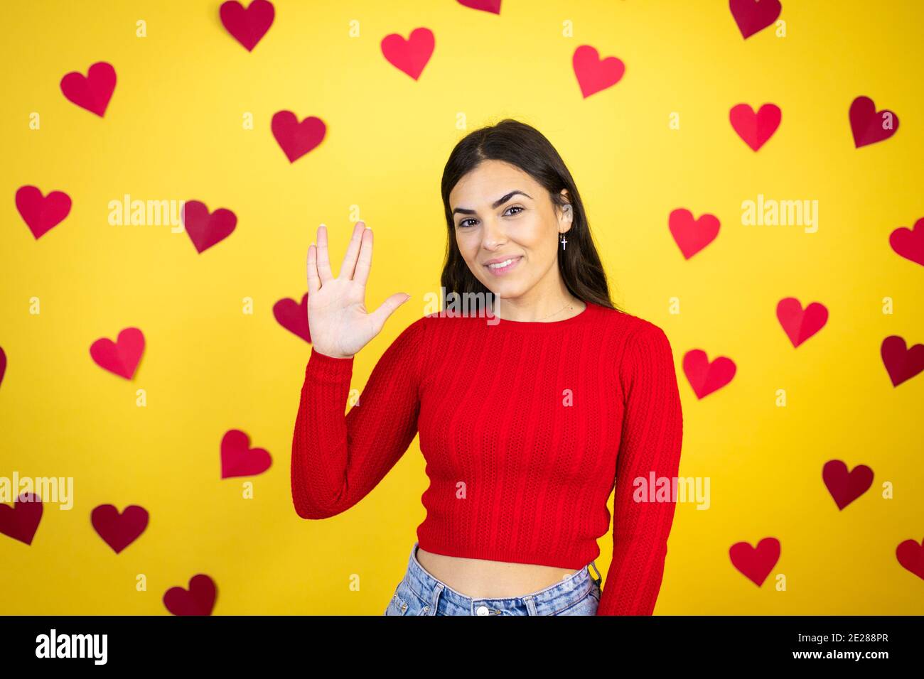 Young caucasian woman over yellow background with red hearts doing star ...