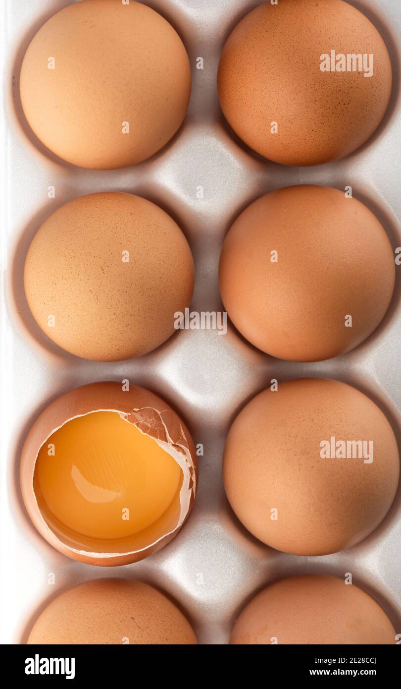 Top view of a chicken egg shell with yolk among whole eggs. Close up ...