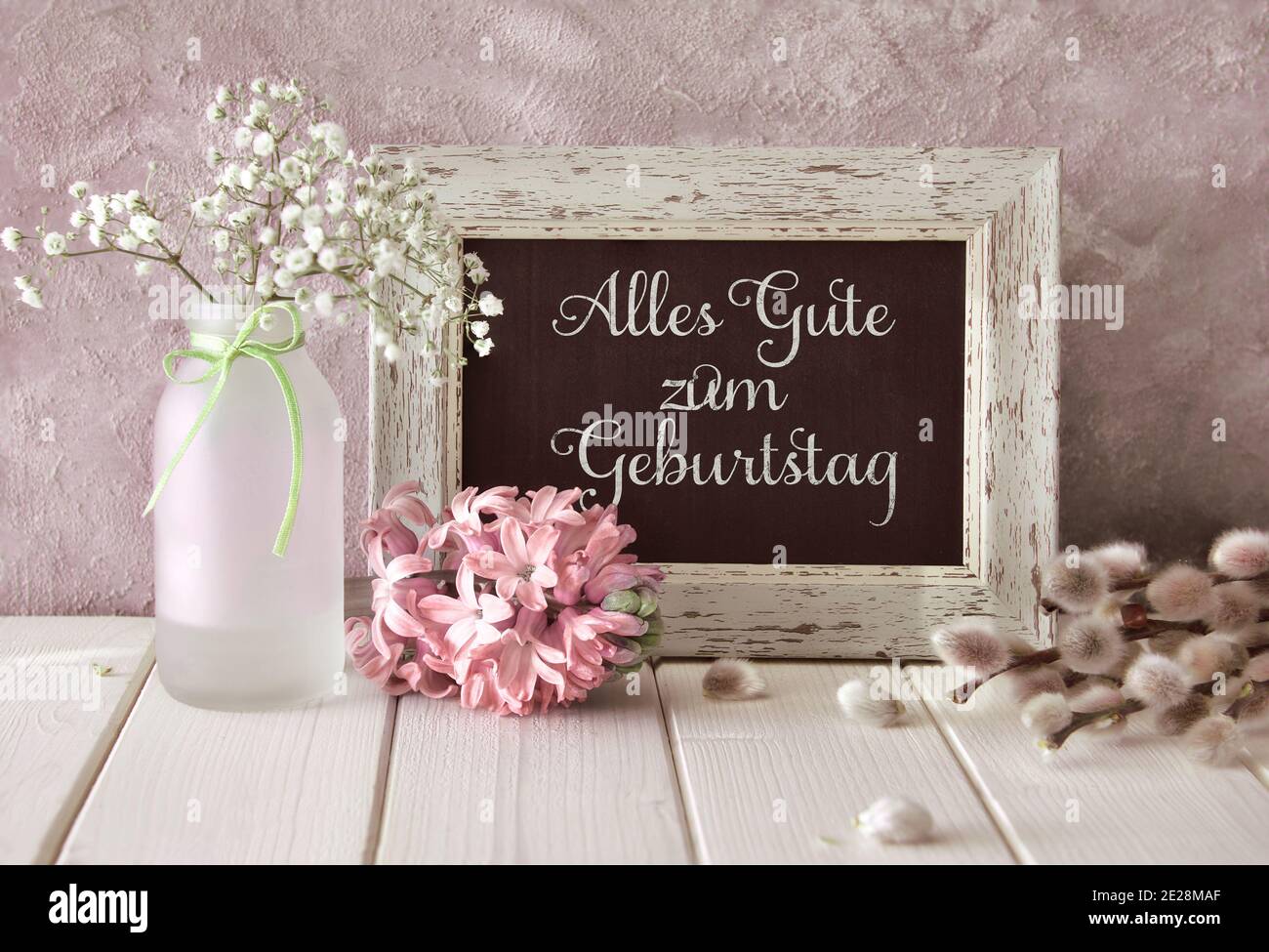 Spring flowers and a blackboard on white table, sprngtime background ...