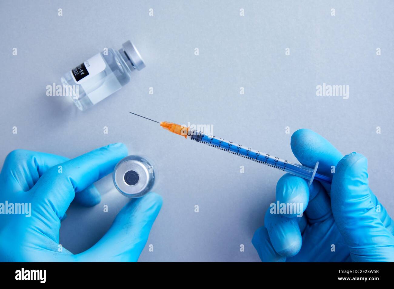 Gloved hands hold a vial of clear vaccine and syringe for science Stock ...