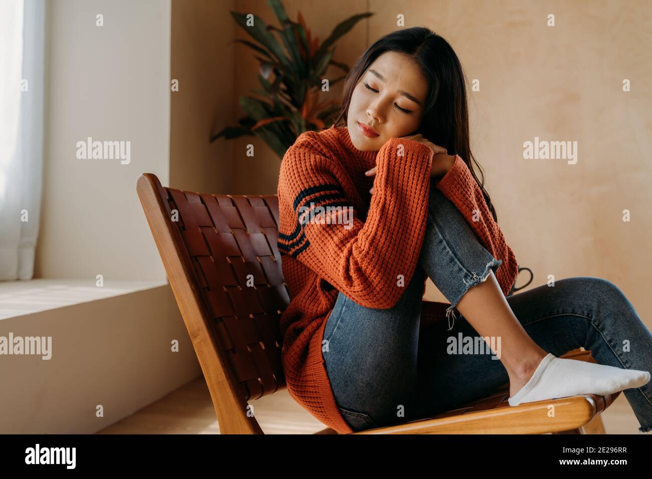 Depressed sad girl feeling lonely sitting by home winter looking out ...