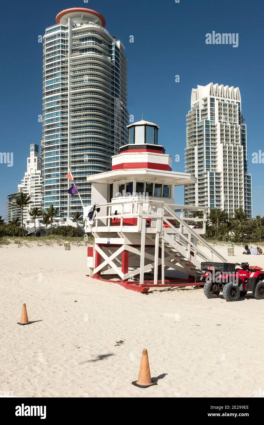 A red and white striped lifeguard tower with tall condos in the ...