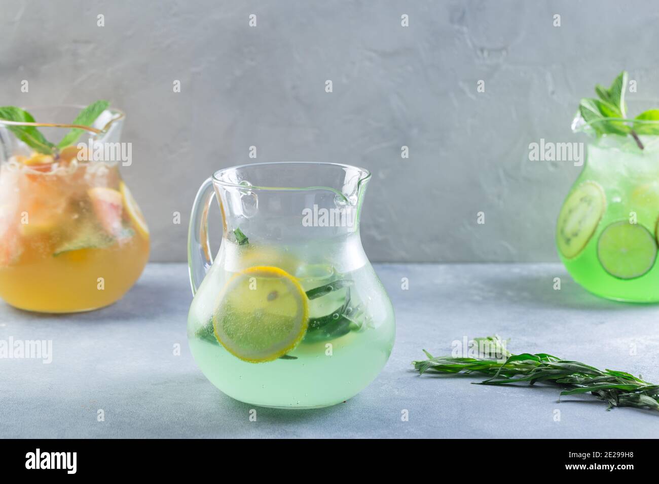 Different color lemonade in glass decanters with fruits and fresh mint ...
