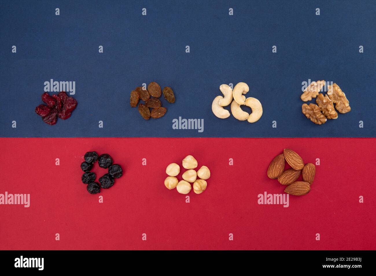 High angle shot of different nuts and seeds on a blue and red surface ...