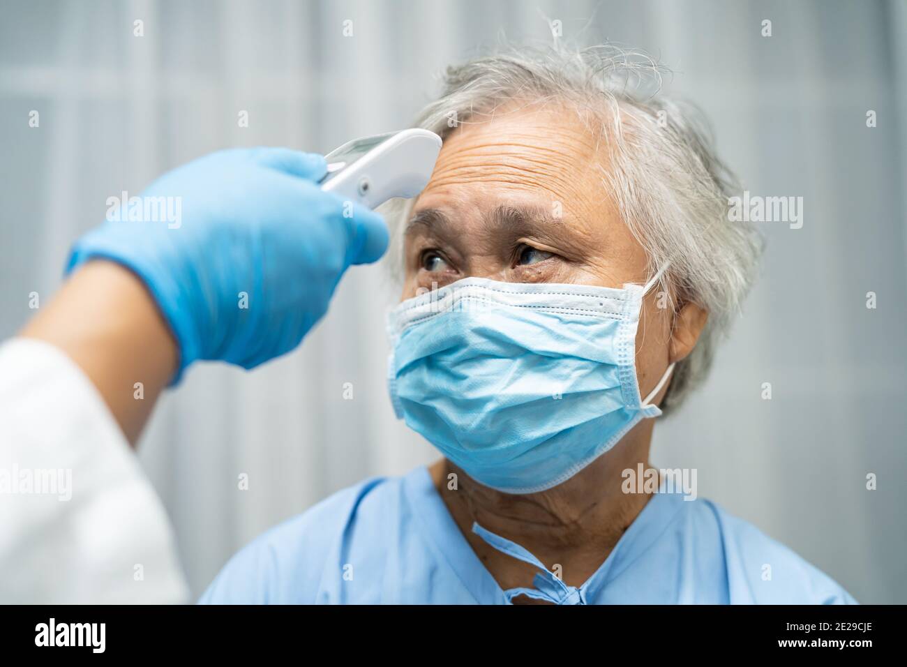 Doctor holding digital thermometer to measures asian senior or elderly ...