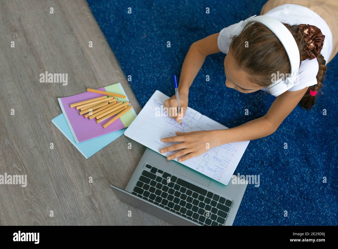 Pupil girl doing homework on the floor at home in front of a laptop ...