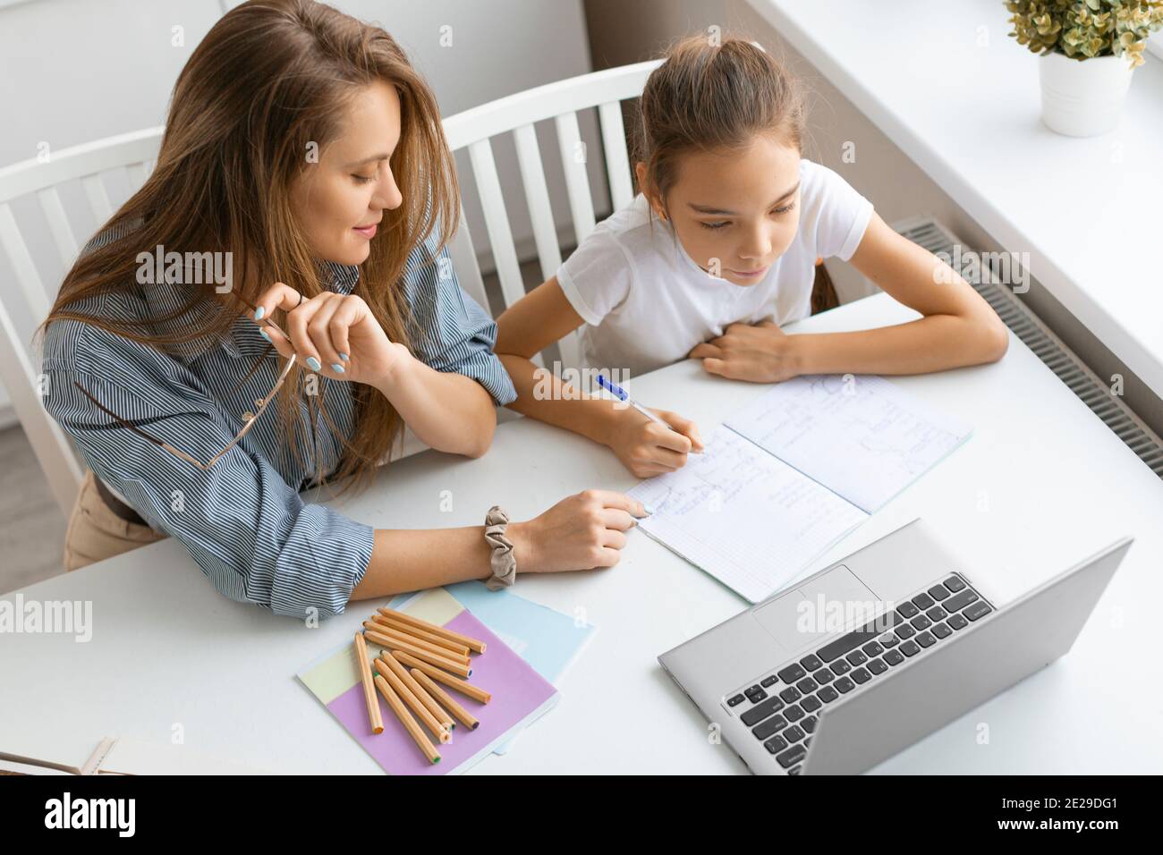 Mom helps her daughter with online homework. Distant education concept ...