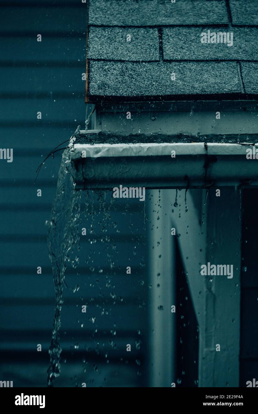 A vertical shot of rainwater flowing out of the gutter Stock Photo - Alamy