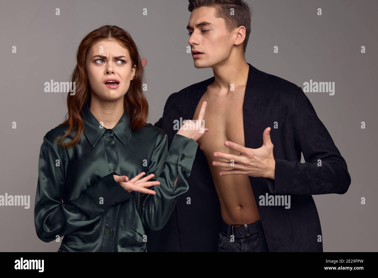 Conflict situation young people in suits on a gray background gestures ...