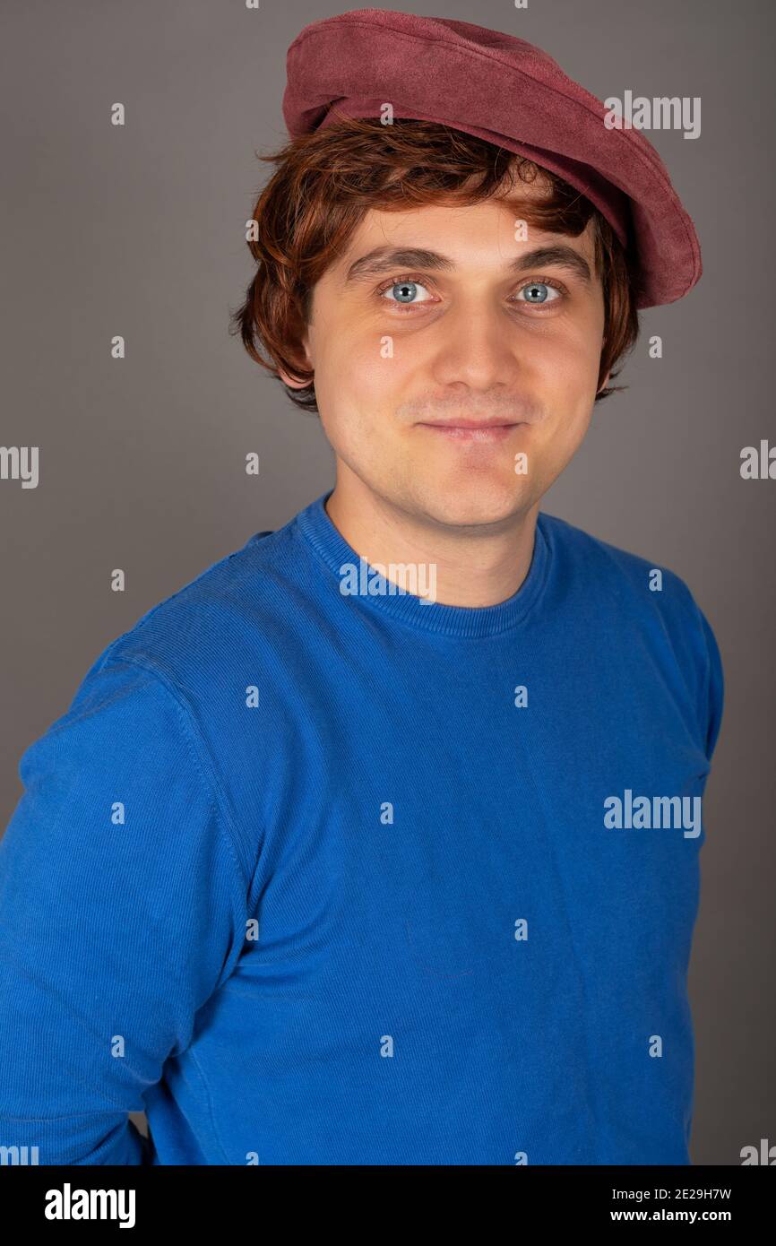 Portrait of a young handsome male actor wearing wig and hat, posing in ...