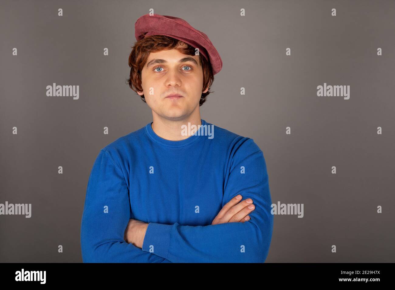 Portrait of a young handsome male actor wearing wig and hat, posing in ...