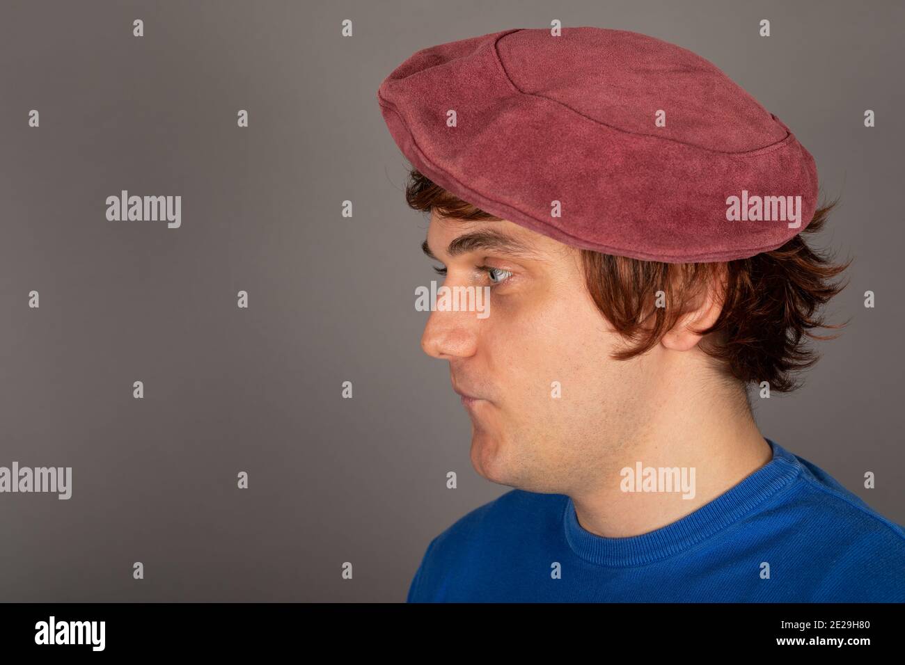 Portrait of a young handsome male actor wearing wig and hat, posing in ...