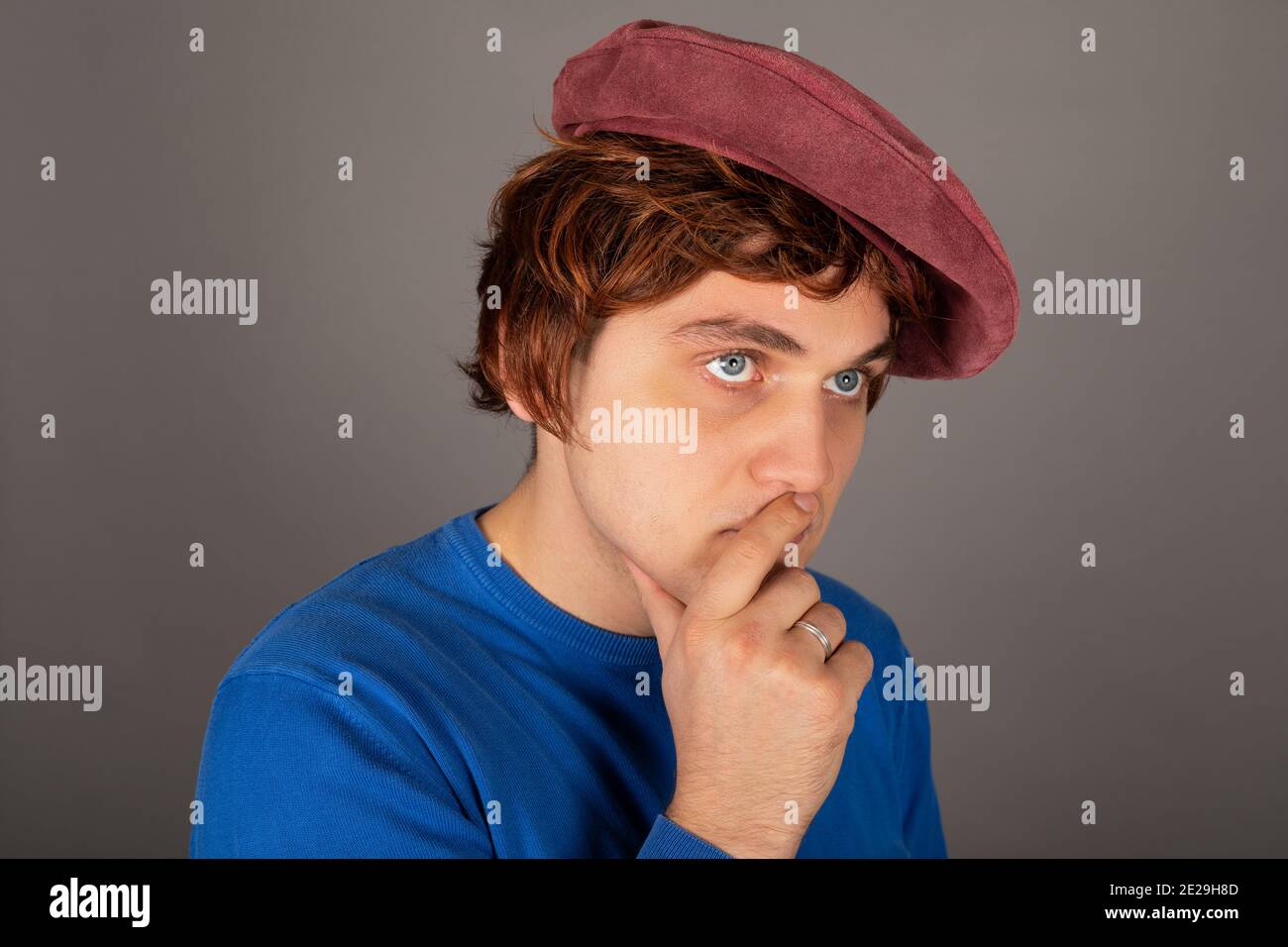 Portrait of a young handsome male actor wearing wig and hat, posing in ...
