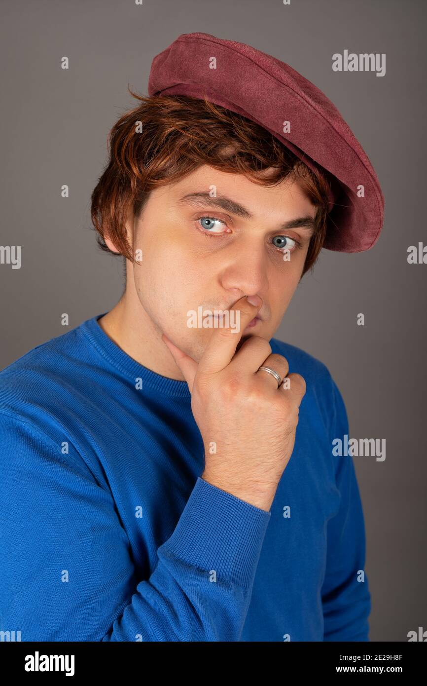 Portrait of a young handsome male actor wearing wig and hat, posing in ...