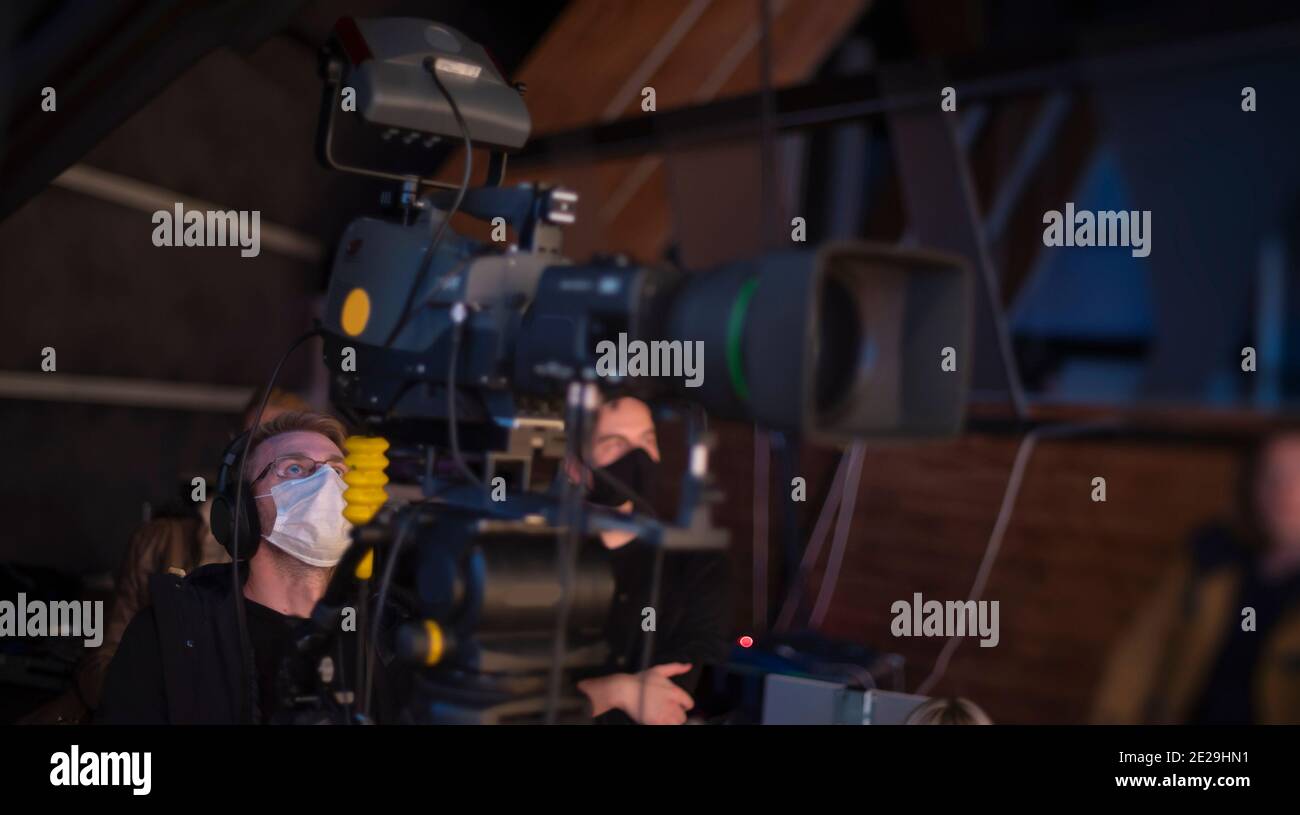 masked cameraman is filming a television show in the studio. TV Stock ...