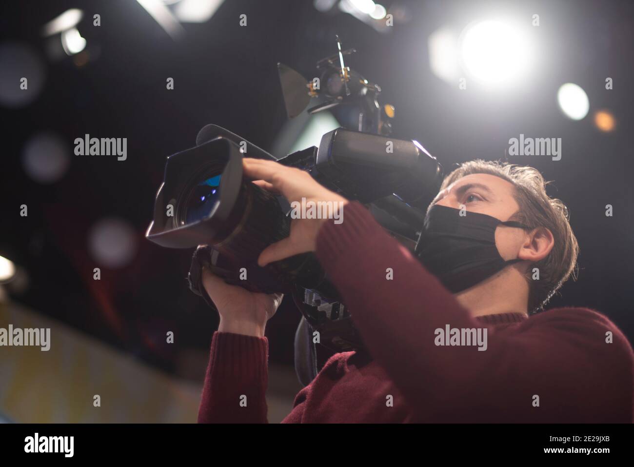 masked cameraman is filming a television show in the studio. TV Stock ...