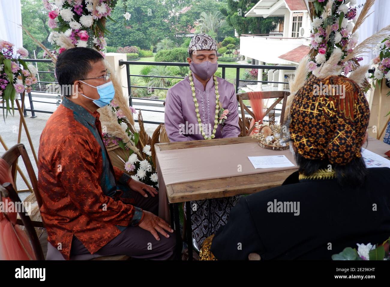A groom with traditional Javanese dress is sitting with his father ...