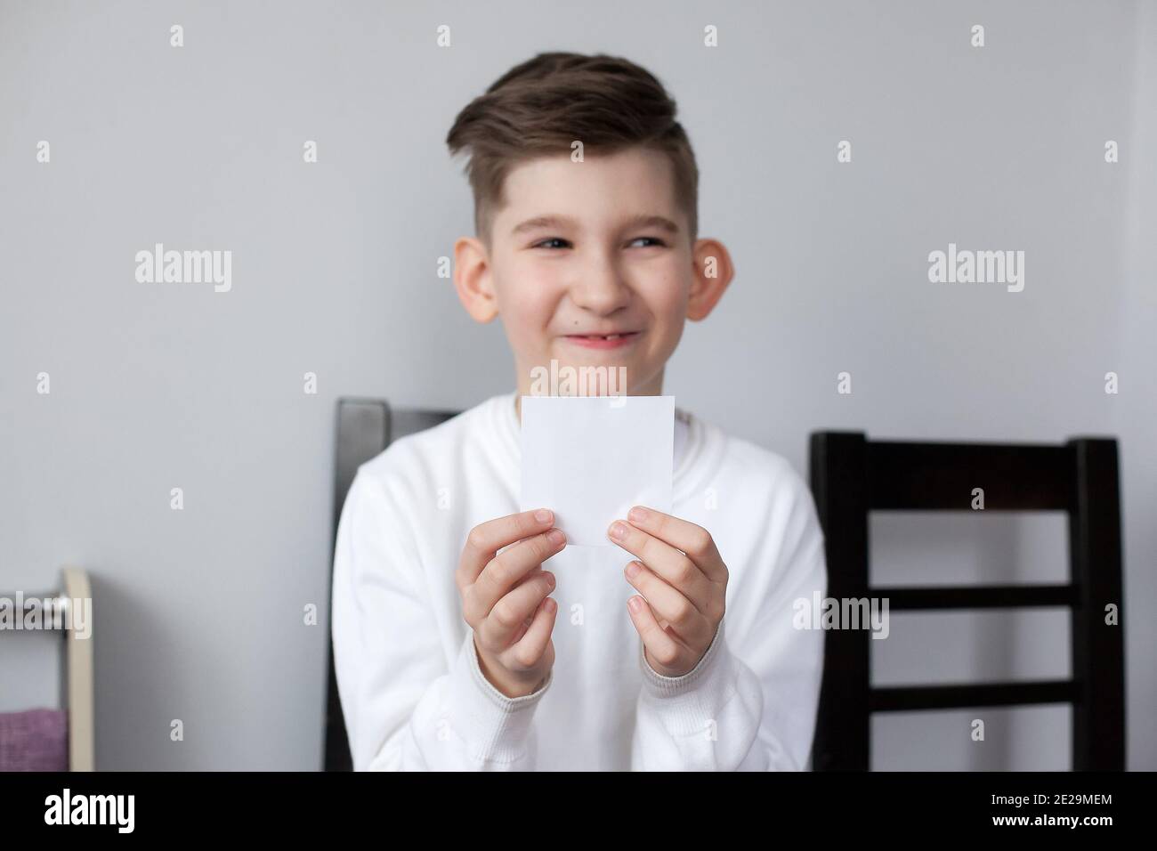Funny boy holding sheet of white paper for your text Stock Photo - Alamy