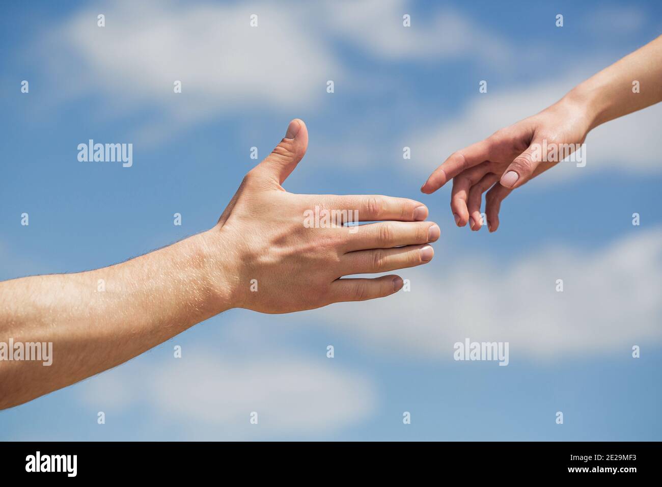 Giving a helping hand. Hands of man and woman on blue sky background ...