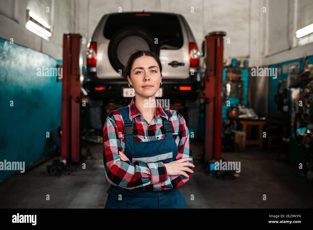 Portrait of a young female mechanic in uniform, posing with her arms ...