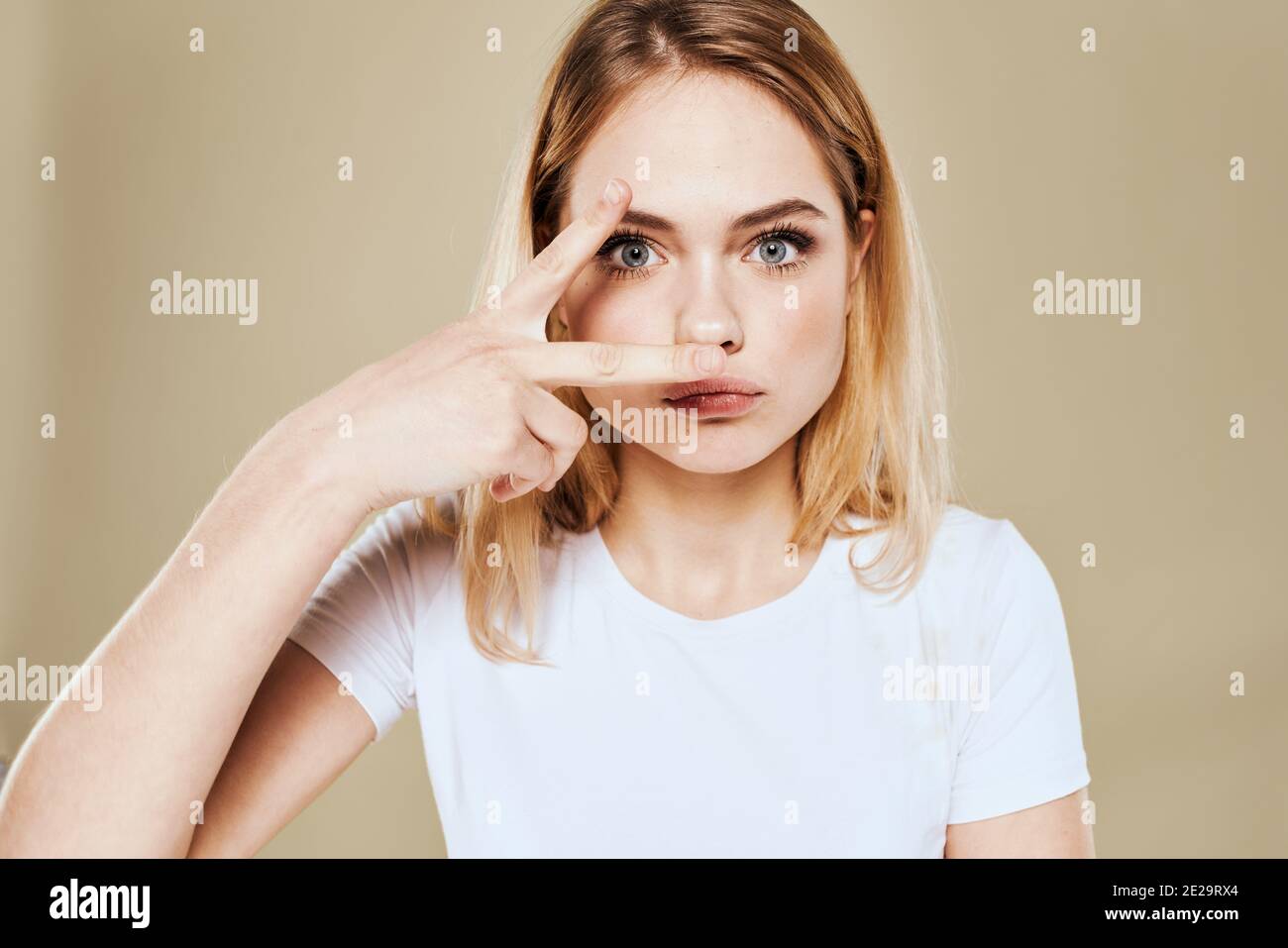 Cheerful blonde woman in a white T-shirt gestures with her hand emotions beige background Stock ...