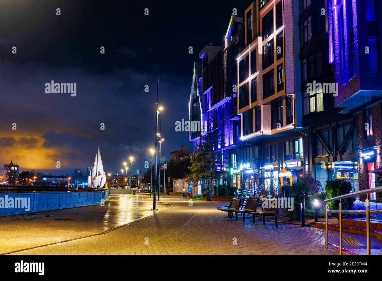 illuminated night street, promenade with street lamps and benches next ...