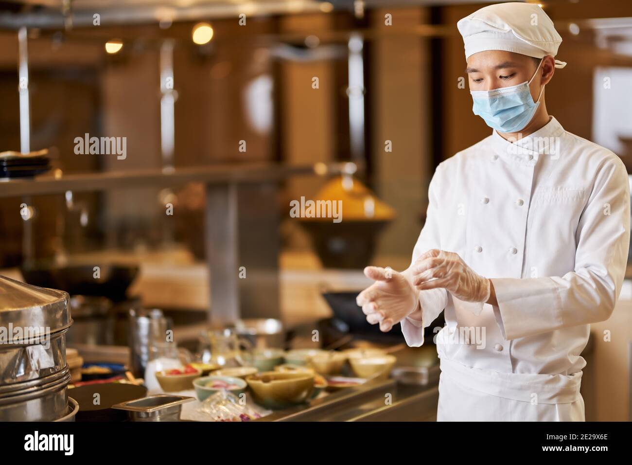Copy-space photo of professional chef in respiratory mask putting on ...