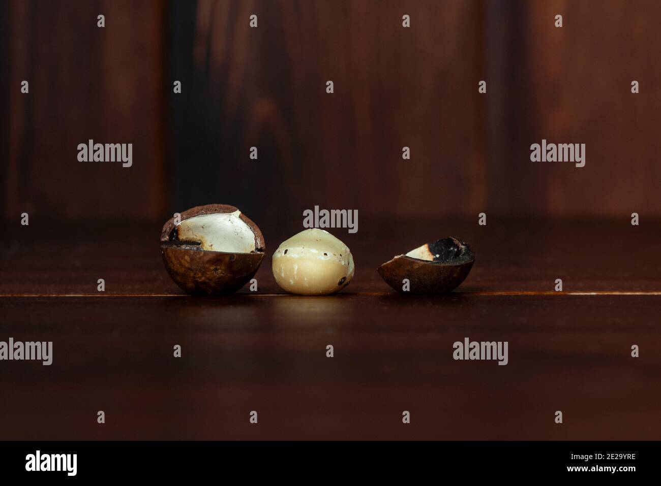 Shelled macadamia nut with nutshell on wooden background. One macadamia ...