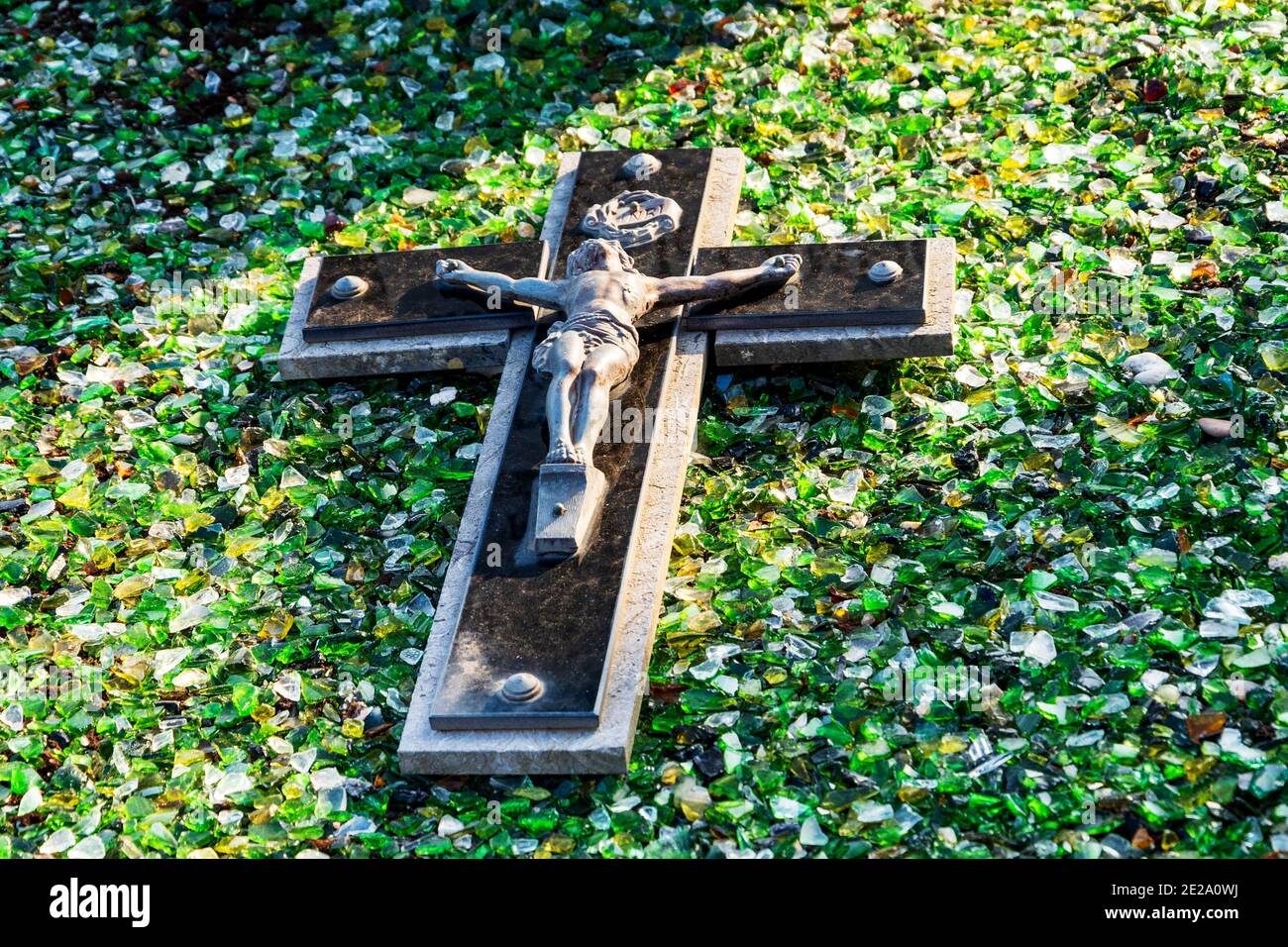 Crucifix on tombstone covered with shiny glass shards. Typical burial memorial tradition at ...