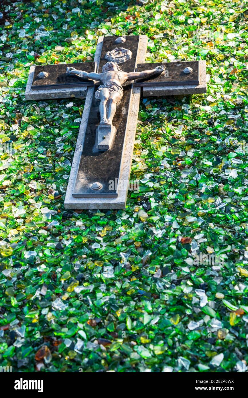 Crucifix on tombstone covered with shiny glass shards. Typical burial memorial tradition at ...