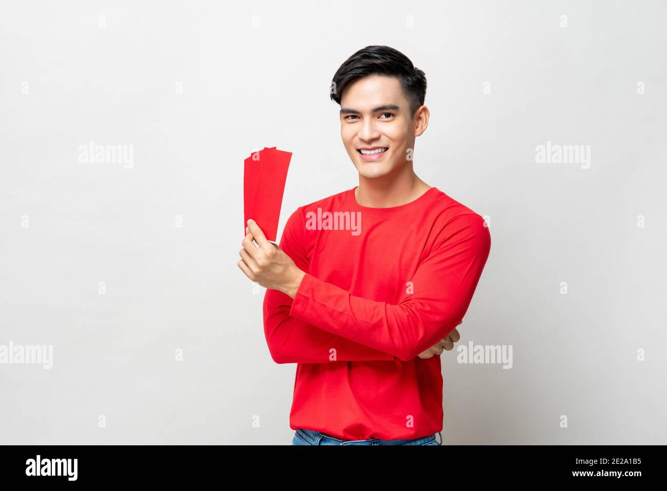 Smiling handsome Asian man holding red envelopes or Ang Pao in studio ...