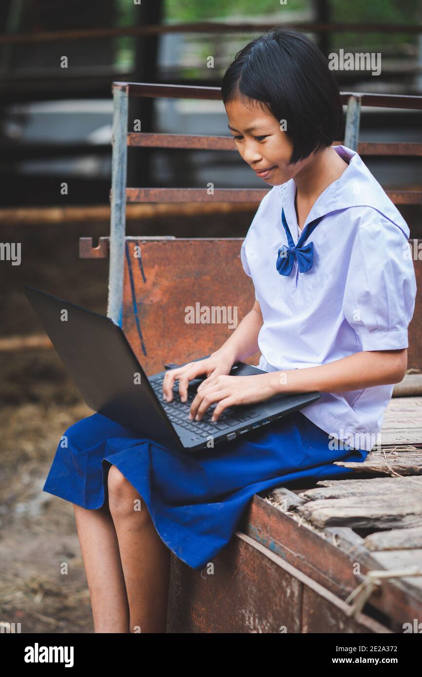 Asian uniform student girl using computer notebook with smile and happy ...