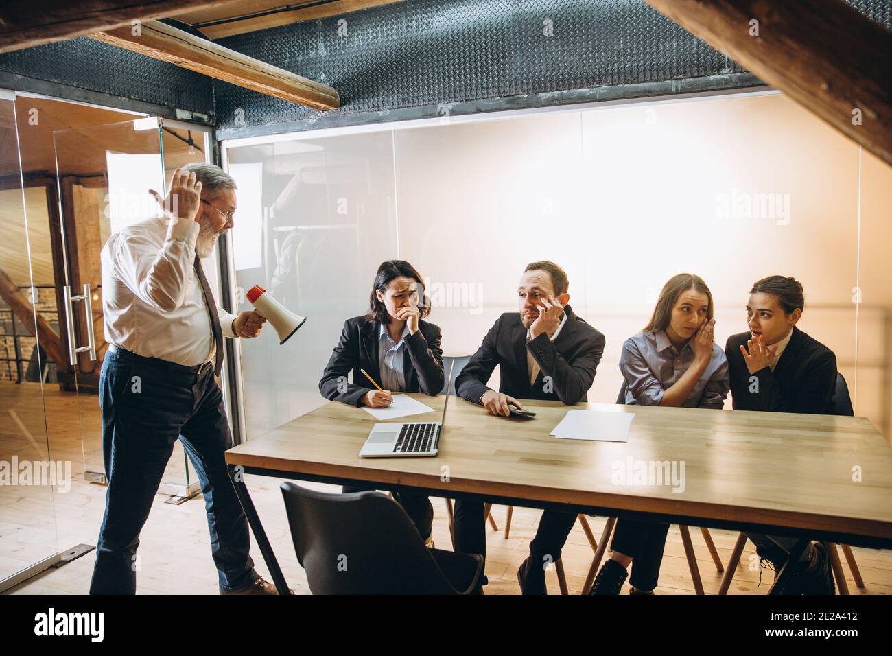 Loud. Angry boss with megaphone screaming at employees in office ...