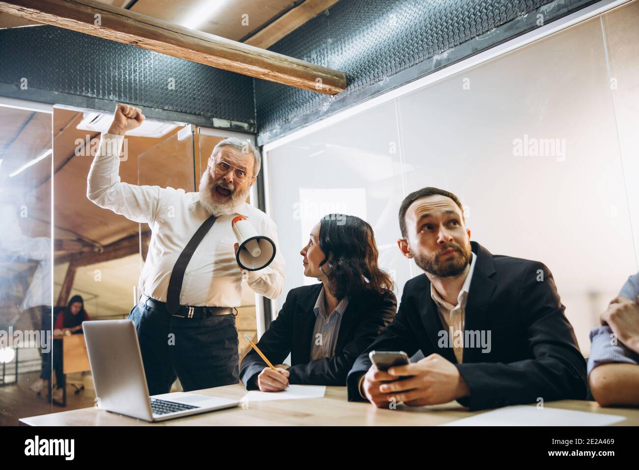 Shouting. Angry boss with megaphone screaming at employees in office ...